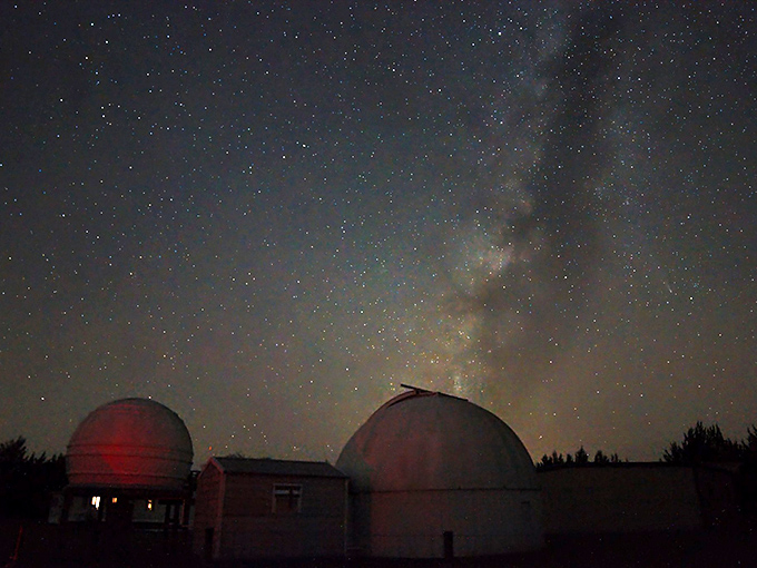 Where two white domes stand sentinel against the night, the Milky Way unfurls its cosmic banner overhead.