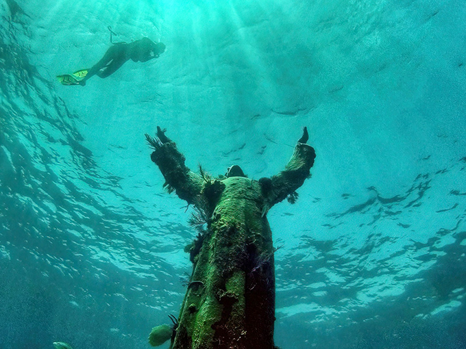 Christ of the Abyss stands serenely beneath the waves, arms outstretched as if blessing the curious divers who visit this underwater sanctuary.