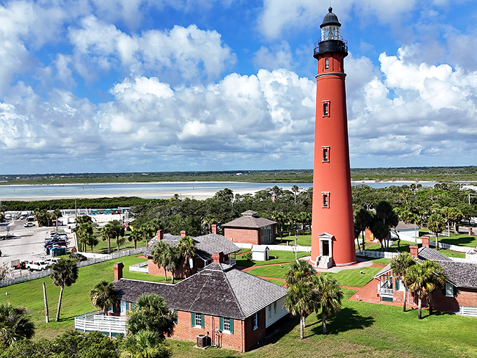 The majestic Ponce de Leon Inlet Lighthouse stands tall against Florida's blue sky, a coral-colored sentinel guarding the coastline since 1887.