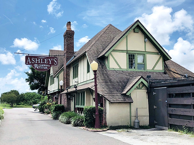 Ashley's Tudor-style exterior stands like a charming English transplant amid Florida's palm trees, its weathered sign hinting at stories within.
