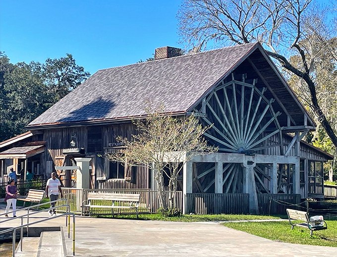 The rustic charm of Old Sugar Mill's exterior welcomes visitors with its distinctive water wheel design and weathered wooden character.