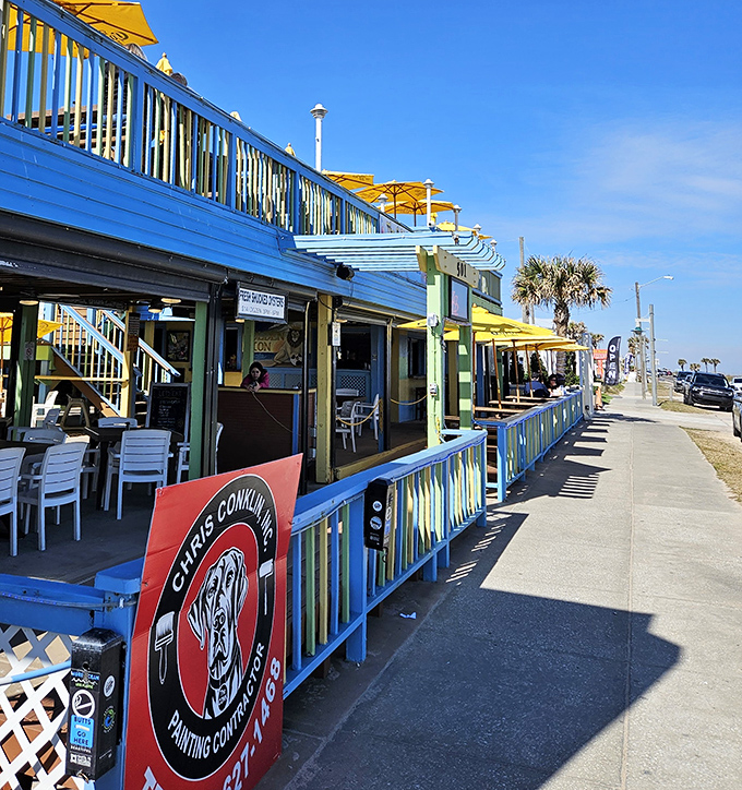 The vibrant blue exterior of Golden Lion Caf&eacute; welcomes beach-goers with its colorful railings and promise of seafood treasures within.