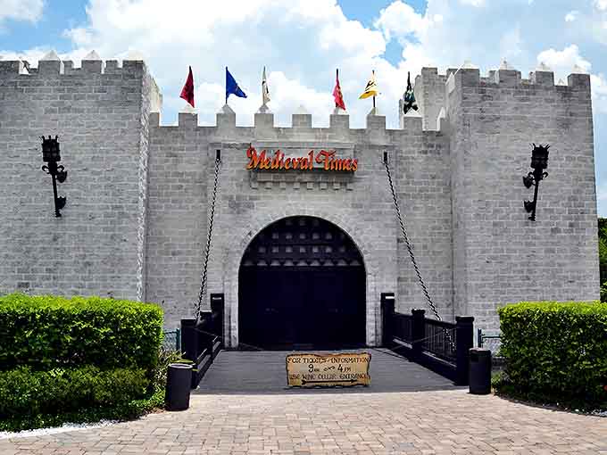 The imposing castle entrance at Medieval Times beckons visitors with its stone facade and colorful flags &ndash; medieval fantasy meets Florida sunshine in architectural form.
