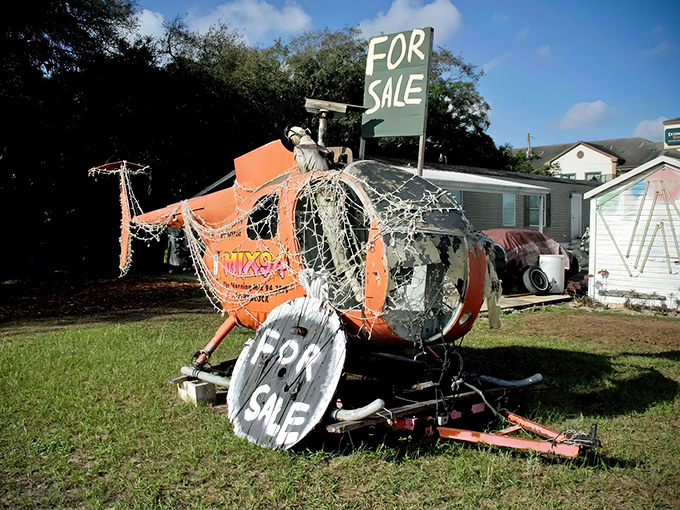 A weathered helicopter shell sits forlornly in the grass, sporting "FOR SALE" signs &ndash; the ultimate conversation starter for your front yard.