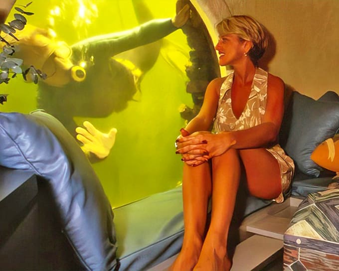 A visitor enjoys the surreal experience of watching divers through the large porthole window at Jules' Undersea Lodge in Key Largo.