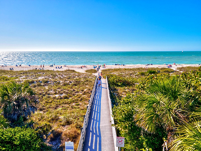 A wooden boardwalk stretches toward turquoise waters, inviting visitors to leave footprints in Nokomis Beach's sugar-white sand paradise.