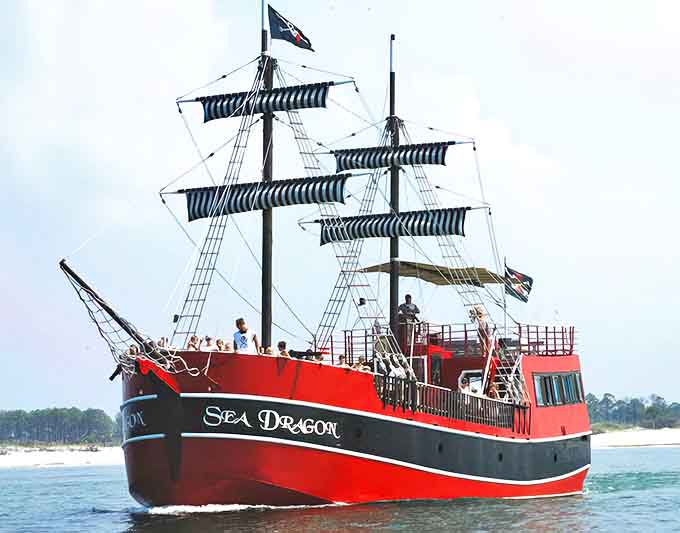 The majestic Sea Dragon cuts through Panama City Beach waters, its crimson hull and striped sails promising adventure for landlubbers of all ages.