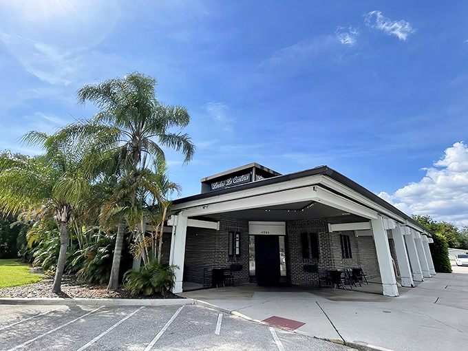 Palm trees frame the unassuming white building with its simple sign &ndash; a culinary time capsule promising treasures that outshine its modest facade.