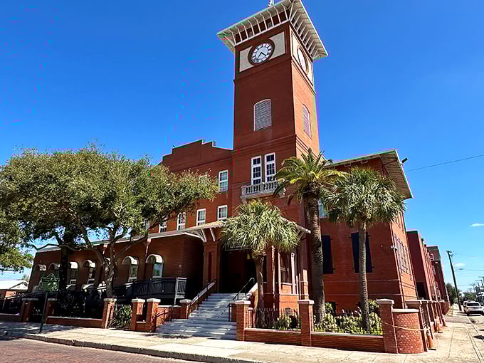 The iconic red brick facade of J.C. Newman Cigar Company stands proudly against the Florida sky, its clock tower keeping watch over Tampa's historic Ybor City.