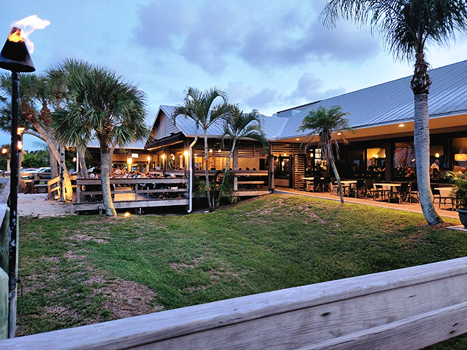 Twilight transforms River Rocks into a glowing oasis, where palm trees stand sentinel over diners enjoying Florida's perfect evening temperatures.