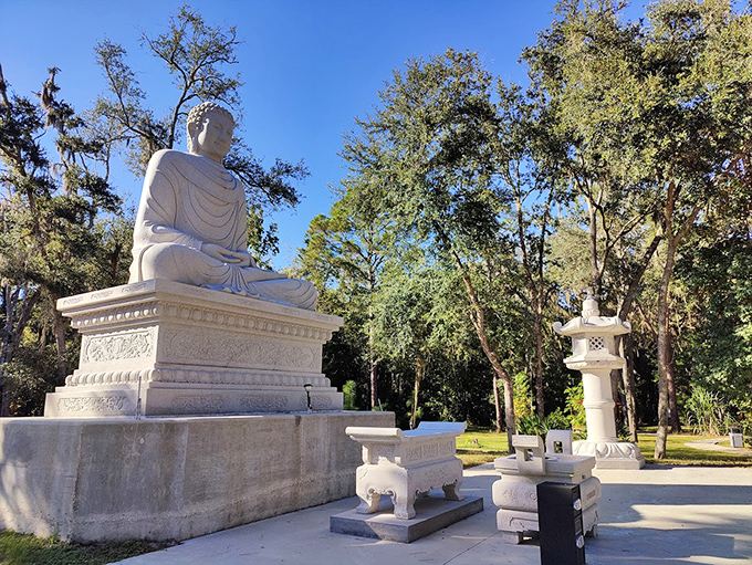 The serene white Buddha statue at Tu Viện A Nan creates a striking contrast against Florida's lush greenery, inviting peaceful contemplation.
