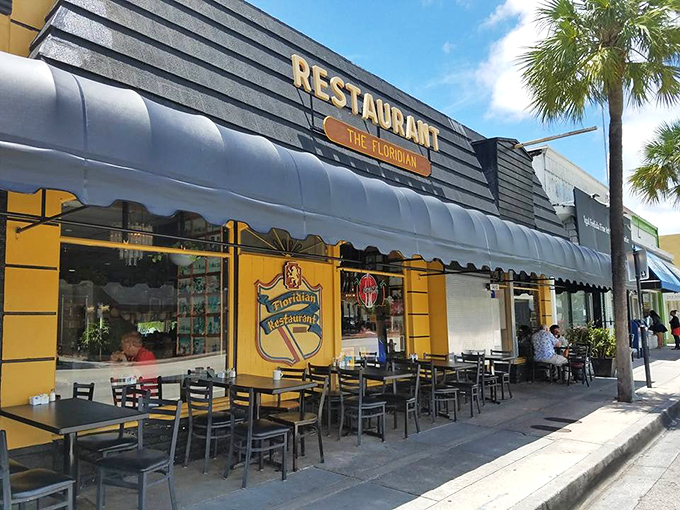 The Floridian's sunny yellow exterior with its distinctive black awning stands like a cheerful beacon on Las Olas Boulevard, promising comfort food paradise within.