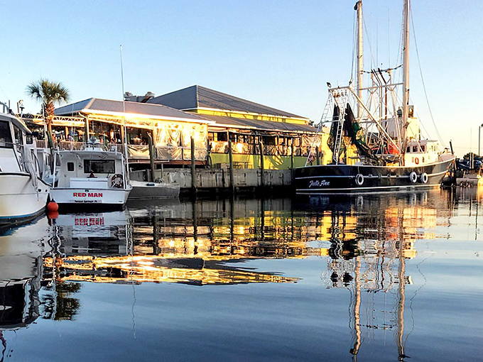 Rusty Bellies' vibrant waterfront setting glows at dusk, with fishing boats nestled alongside the restaurant &ndash; dinner with a maritime show.