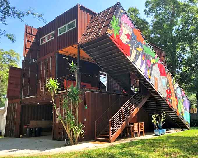 The container house rises from Florida's landscape like an industrial fairy tale, its vibrant staircase mural beckoning adventure-seekers with colorful promises.