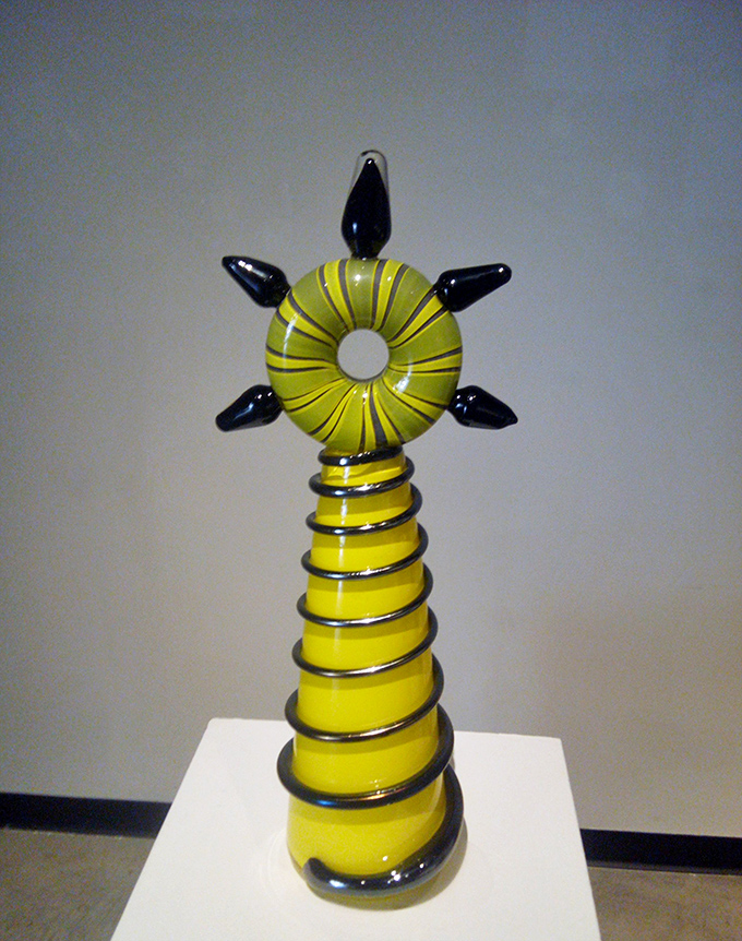 A delicate yellow and green art glass piece showcases the artist's ability to balance technical precision with organic, flowing forms.