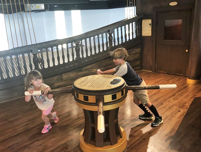 Young sailors work together to navigate the high seas, learning teamwork while spinning this oversized ship wheel.