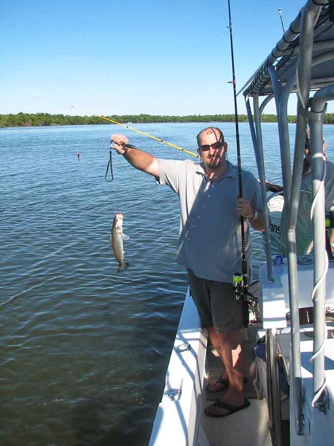 That smile says it all: another successful catch in waters where the fish are plentiful and the fishing stories are even more abundant.