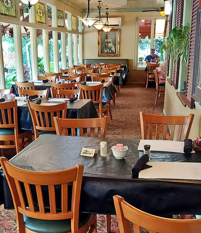 Sunlight streams through stained glass accents, casting colorful patterns across tables where generations of families have broken bread together.