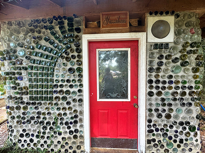 A bright red door framed by an intricate sunburst pattern of bottles welcomes visitors into this unique space where waste becomes wonder.