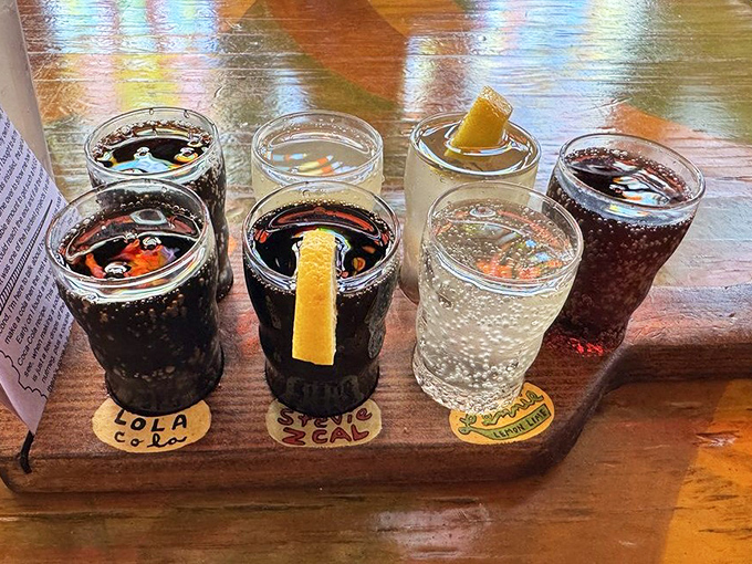 A flight of craft sodas arrives like a rainbow in glassware. Each uniquely labeled cup promises flavor adventures beyond ordinary beverages.
