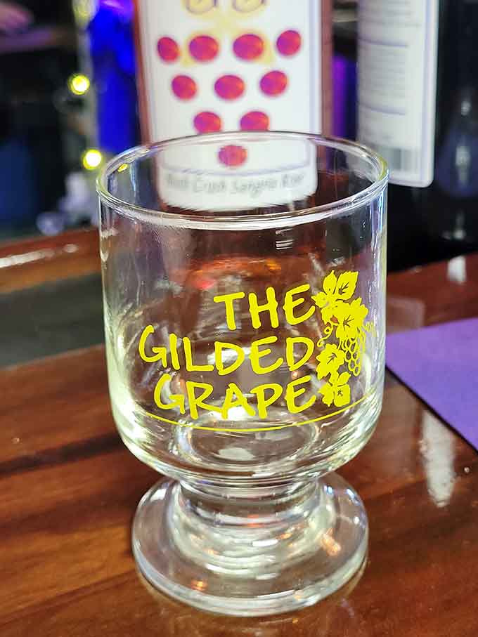 The Gilded Grape logo gleams on glassware that's held countless toasts, celebrations, and moments of pure liquid joy.