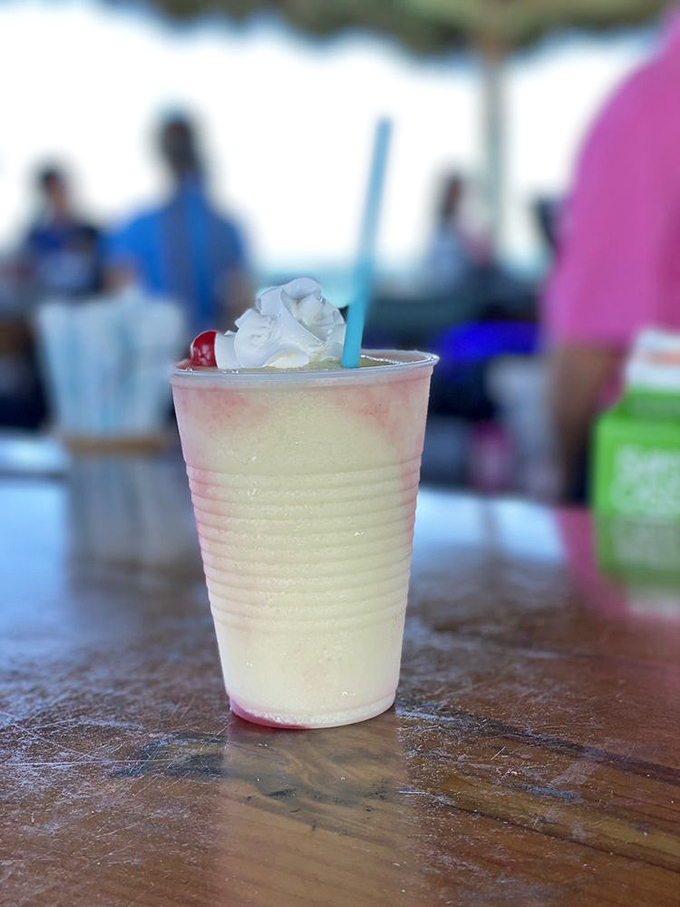 The Miami Vice – half strawberry daiquiri, half piña colada – topped with whipped cream and a cherry, the ultimate vacation in a plastic cup.