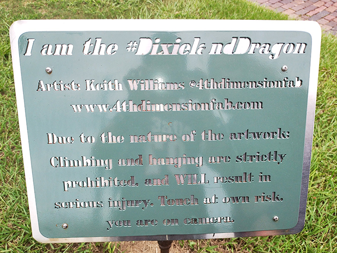 The sign identifies this creation as the #DixielandDragon by artist Keith Williams, with a gentle reminder that dragons, while photogenic, prefer not to be climbed upon.
