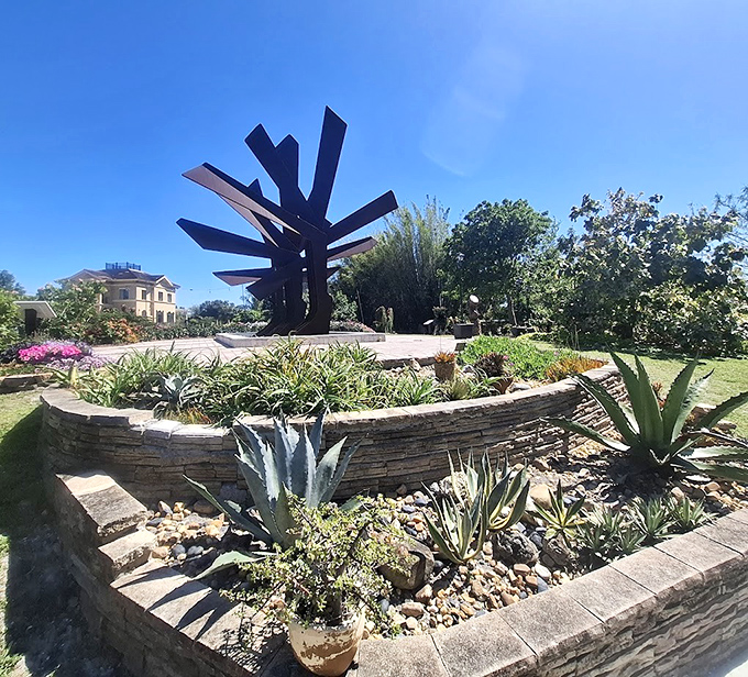 Modern meets ancient in this dramatic steel palm sculpture that stands like a sentinel guarding the garden's artistic treasures.