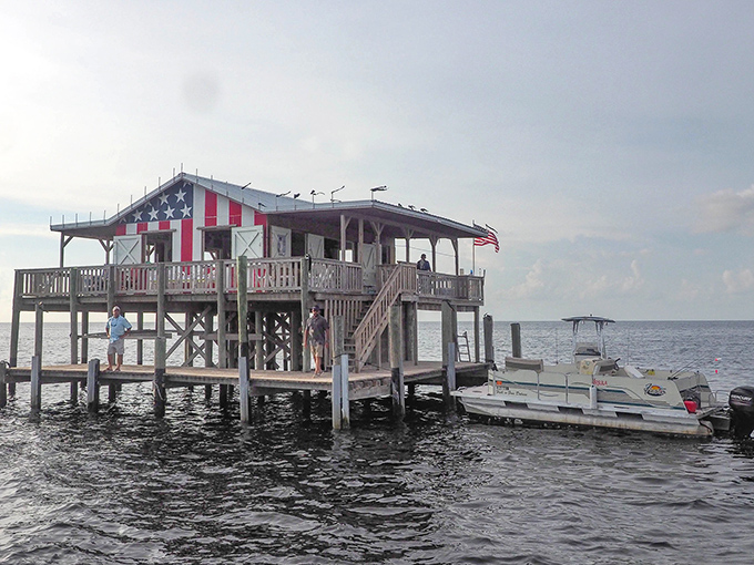 An iconic view of Stilt House No. 6, proudly decorated with the American flag, standing tall above the Gulf waters off Pasco County.