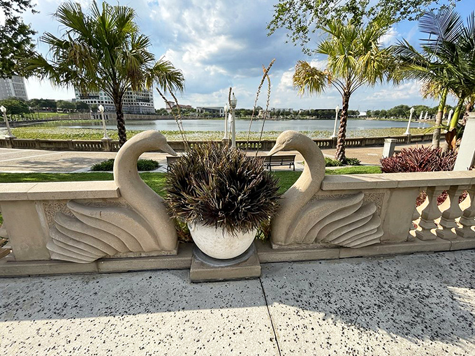 Stone swans stand in eternal grace, their curved necks forming a heart shape that adds romantic whimsy to the garden's edge.