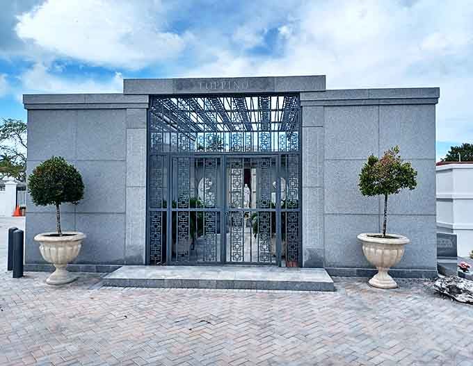 The Toppino mausoleum showcases exquisite craftsmanship with its ornate metalwork and polished granite, a testament to family legacy.