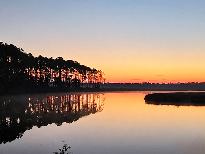 Nature's grand finale as day surrenders to night, painting the sky in impossible colors reflected perfectly in still waters.