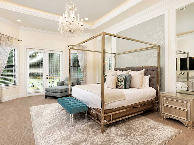 Golden dreams await in this elegant bedroom, where the canopy bed creates a cocoon of luxury under the watchful glow of a crystal chandelier.