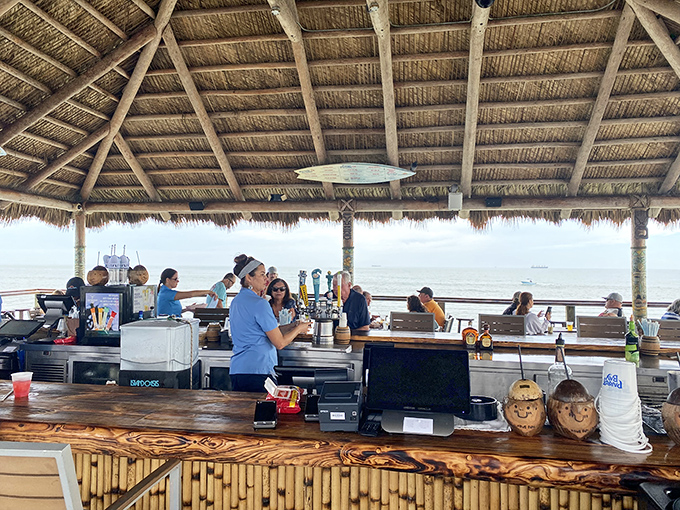 Bartenders work their magic under a traditional thatched roof, with bamboo accents creating an authentic tropical escape miles from ordinary life.