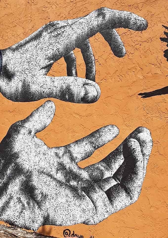 Giant hands reach across a wall in monochrome drama, making you wonder what they're reaching for, probably more wall space for art.