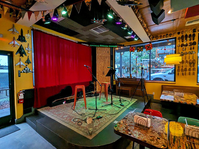 The performance space awaits musicians with its red curtain backdrop. Weekend entertainment adds another sensory layer to the dining experience.