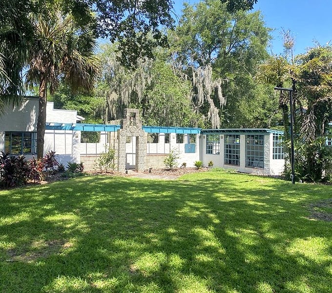 Sunlight dapples across this verdant lawn, where the white museum buildings glow against Florida's impossibly blue sky.