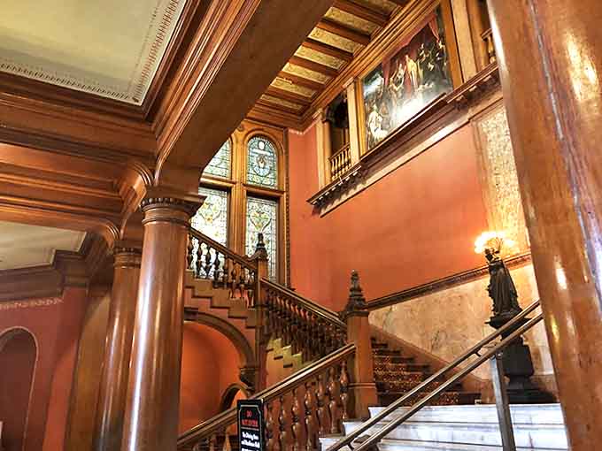 The grand wooden staircase has supported the footsteps of millionaires, students, and possibly a ghost or two seeking higher education.