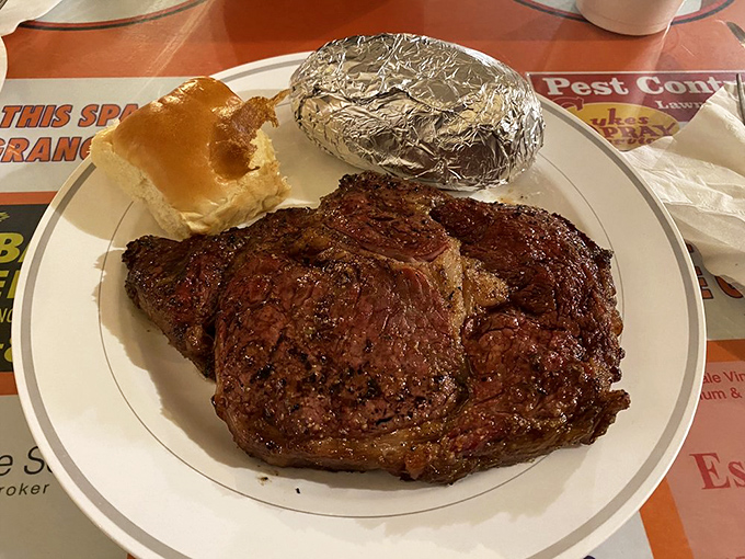 The ribeye steak arrives like a carnivore's dream, with a charred exterior giving way to perfectly pink, juicy meat within.