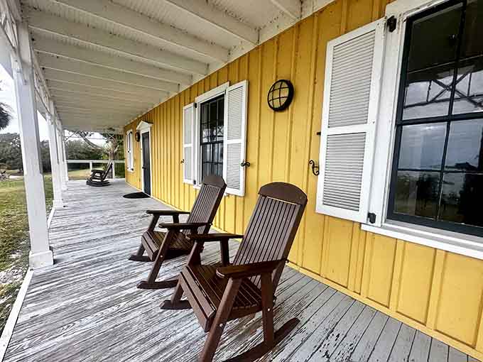 Rocking chairs on a yellow porch overlooking the water: the original stress-relief therapy, no prescription needed.