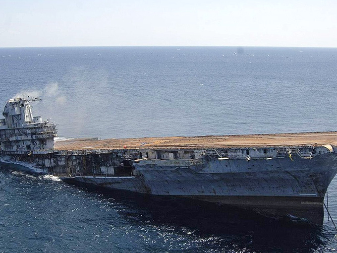 The Oriskany's bow slices through blue waters, its weathered hull telling stories of naval battles before becoming home to marine creatures.