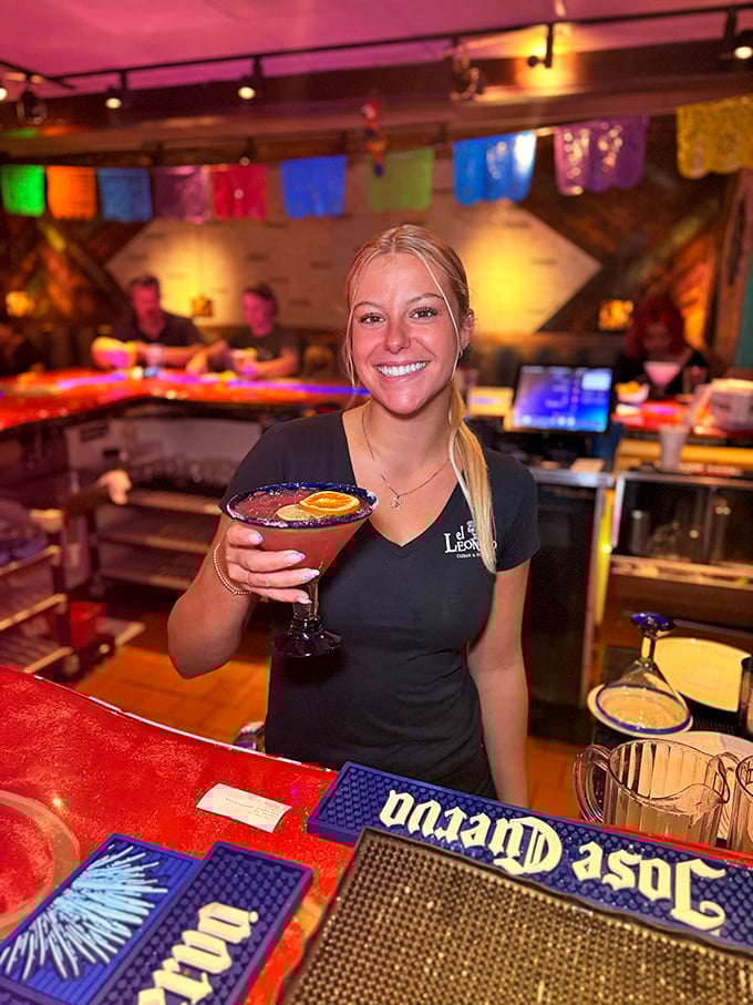 Behind every great restaurant is a dedicated staff&mdash;this server presents a signature cocktail with the pride of a true hospitality professional.