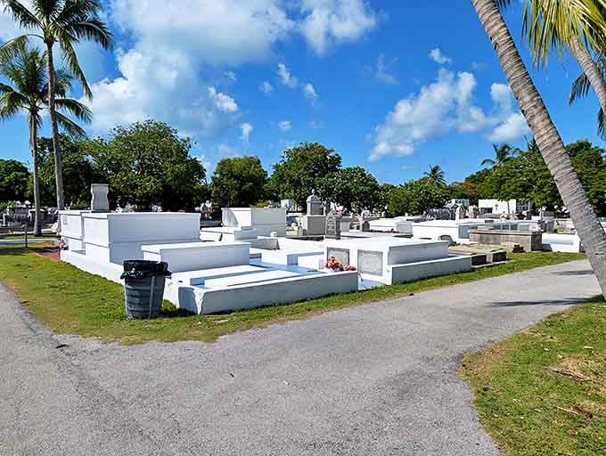 White monuments gleam against lush greenery, creating a serene landscape where visitors can reflect among swaying palm trees.