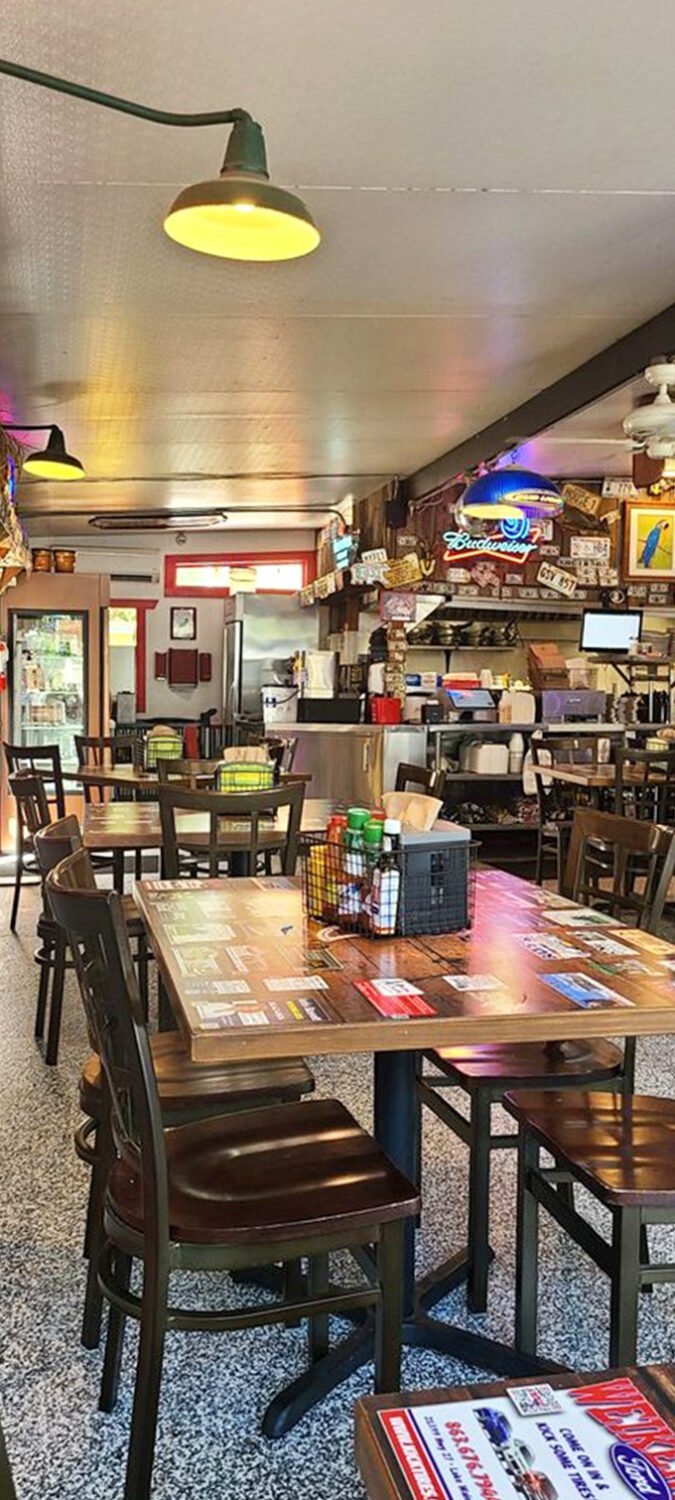 Simple wooden tables set the stage for memorable meals, while walls plastered with memorabilia provide endless conversation starters.