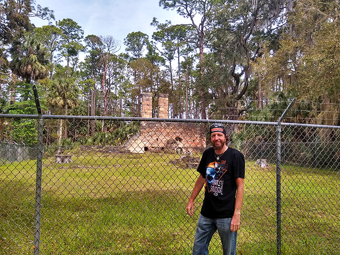 A visitor contemplates the ruins from behind protective fencing, the past tantalizingly close yet forever untouchable.
