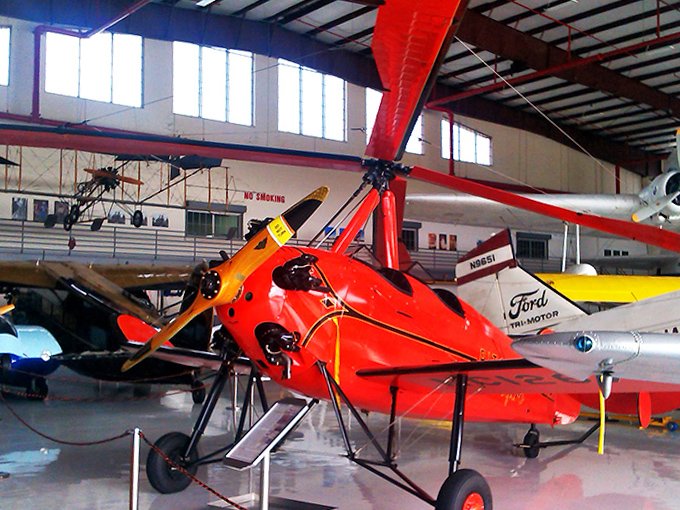 The bright red autogyro looks like something from a science fiction movie, its helicopter-like rotor and airplane propeller representing an evolutionary branch of flight.