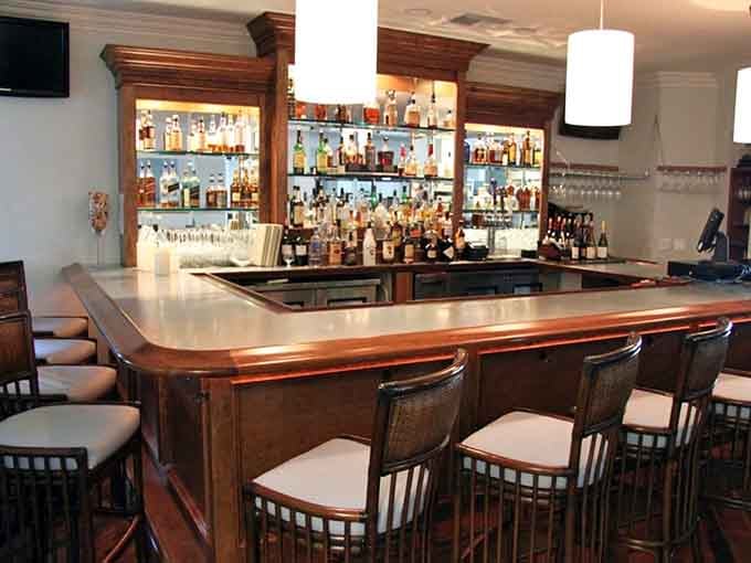 The bar beckons with polished wood and promise, where skilled bartenders craft cocktails worth savoring slowly.