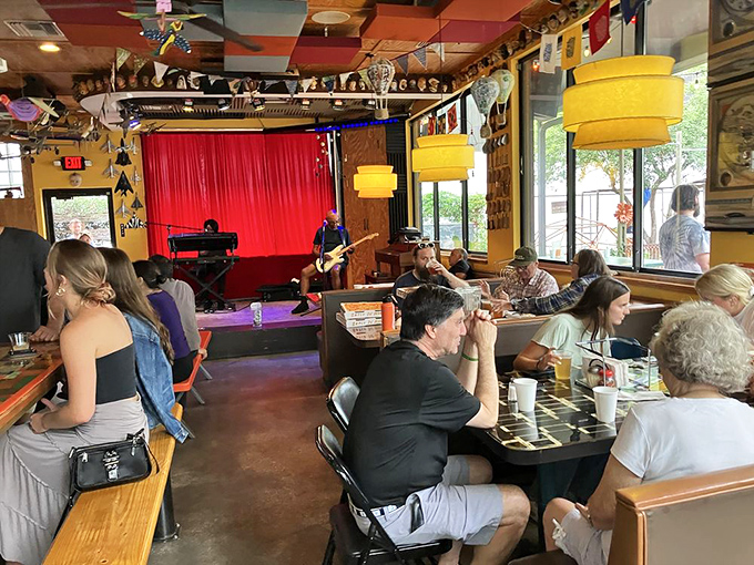 Diners enjoy live music while savoring their meals. The communal atmosphere turns strangers into temporary friends united by pizza appreciation.