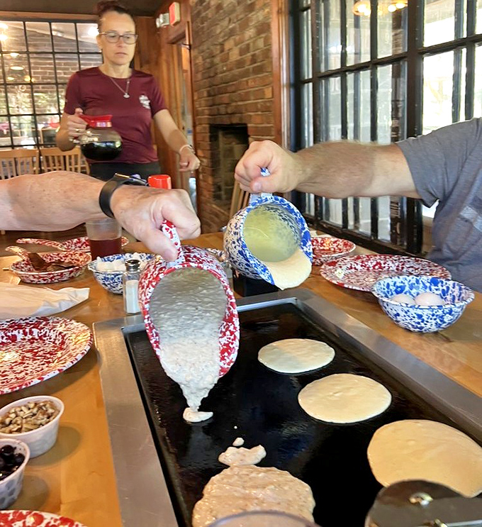 The pancake-making ritual in action – pouring, waiting, flipping – a culinary performance art that never gets old.