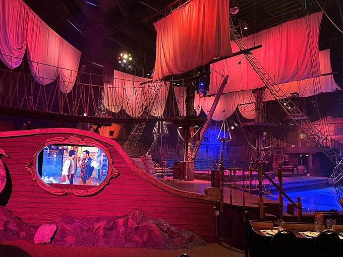 The elaborate ship set features multiple levels, rigging, and dramatic lighting that transforms the space into a Caribbean adventure.